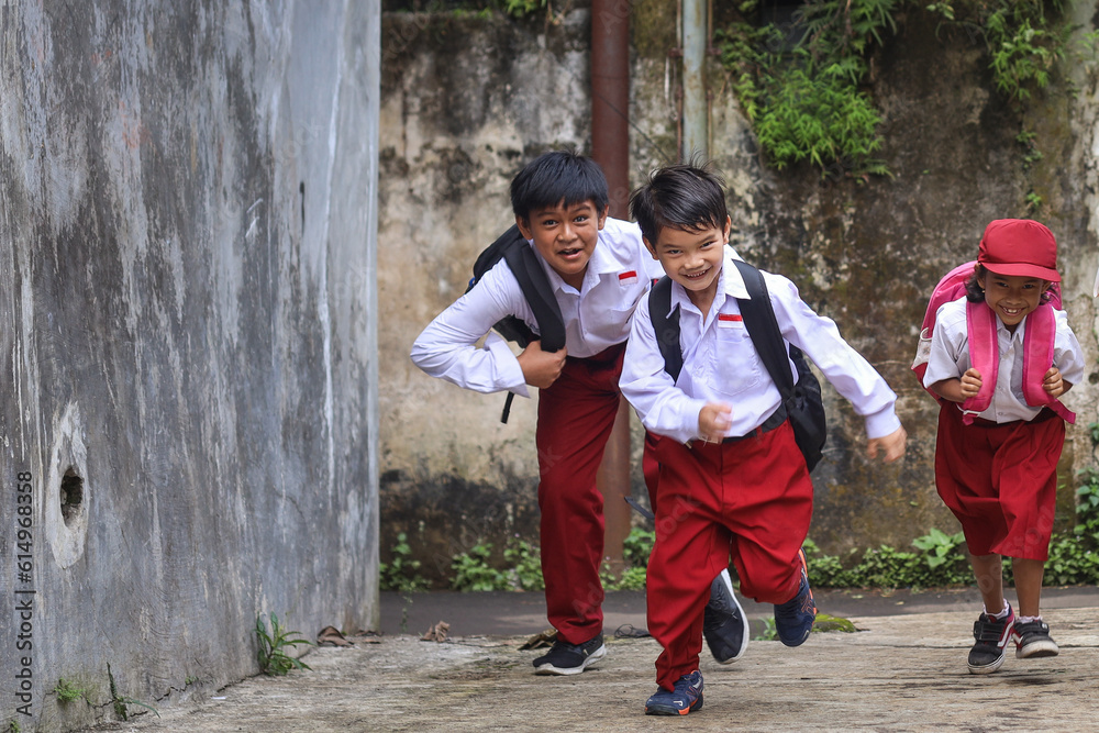 Primary school kids, wearing school uniforms and backpacks, running on ...
