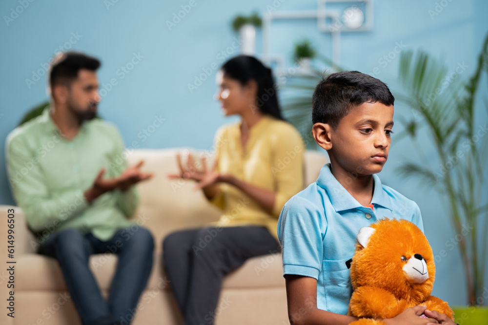 Poster Indian sad kid with doll in front shouting and arguing couple at ...