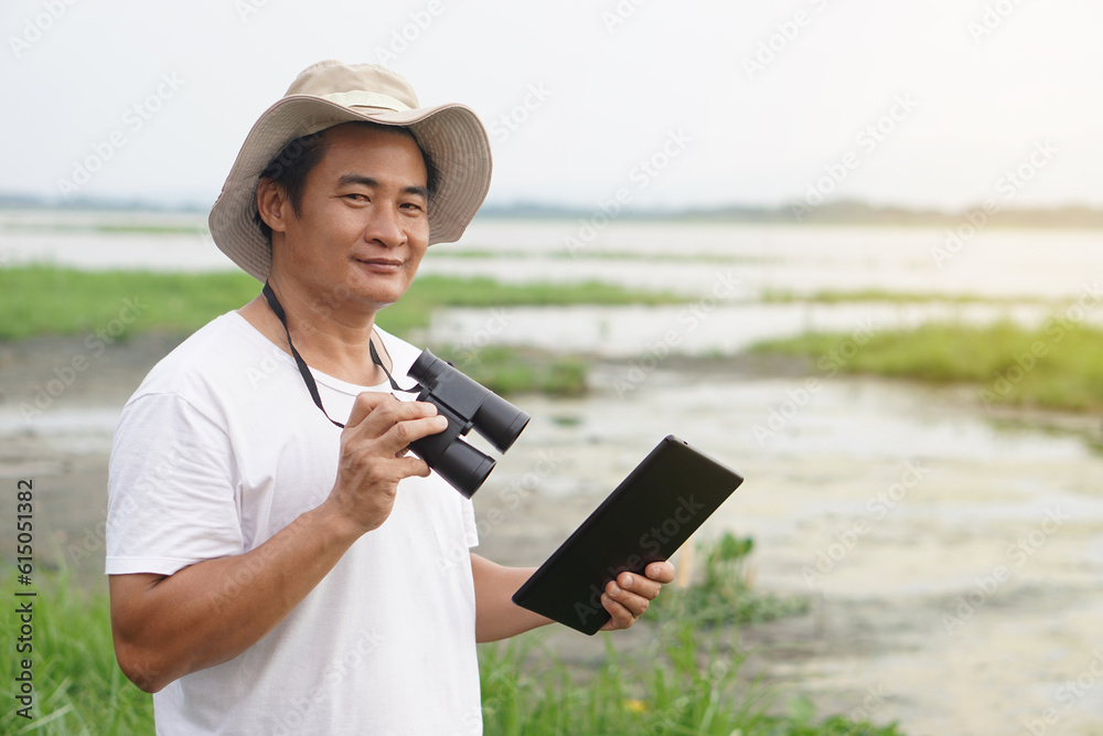 Foto de Handsome Asian man ecologist is surveying nature at the lake ...