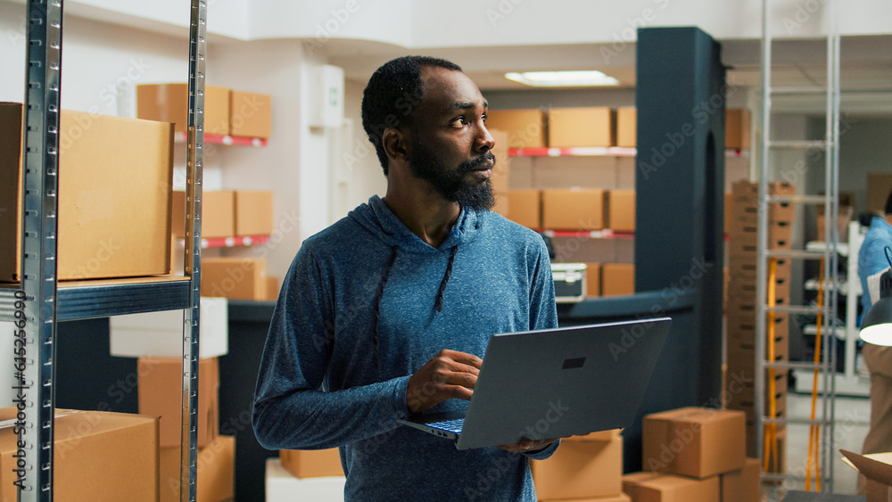 Foto de Male storage room worker using laptop to write products data ...
