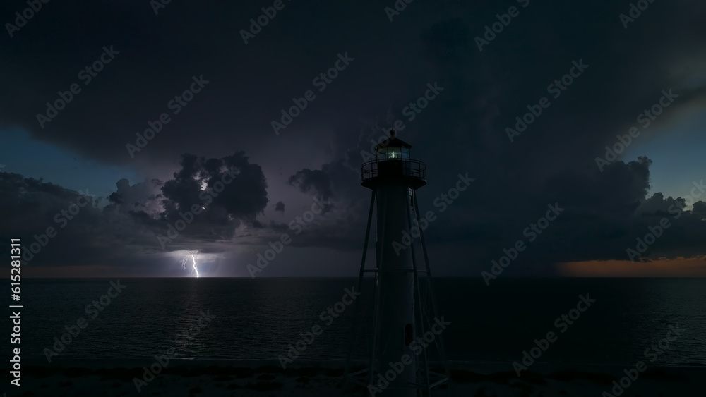 White tall lighthouse on sea shore with blinking light at stormy night ...
