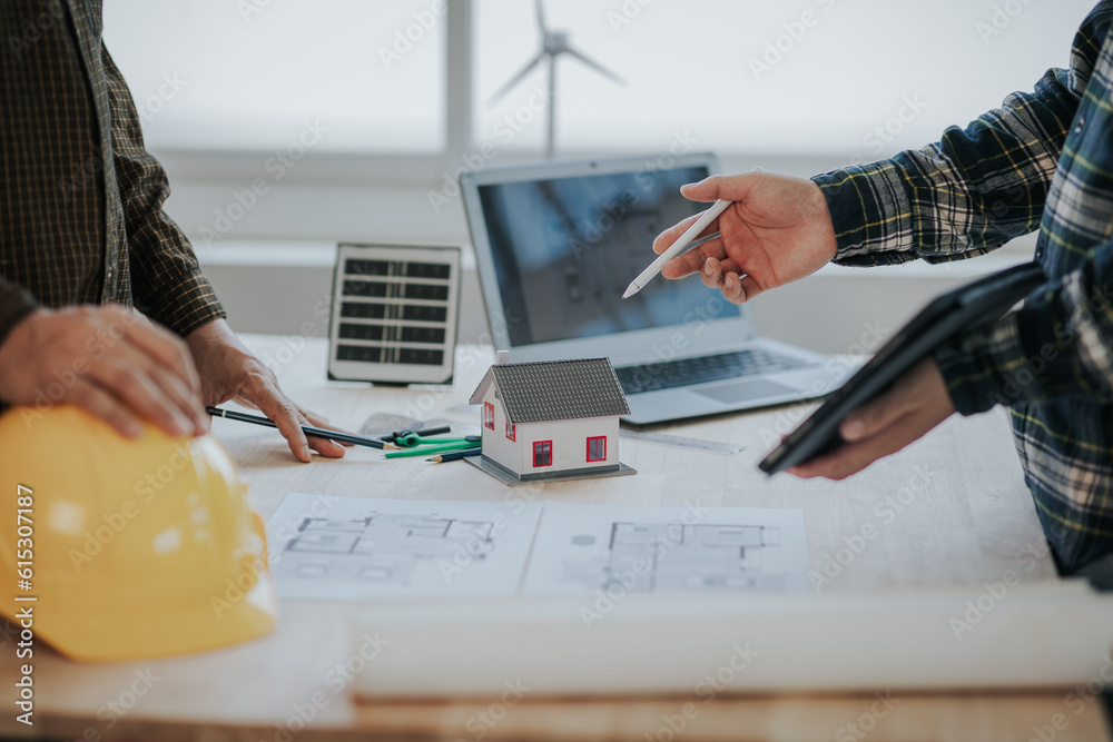 Engineer working in office at desk with solar laptop and concept home ...