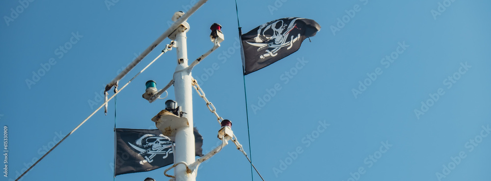 Jolly Roger or pirate ship flag waving with flagpole and blue sky ...