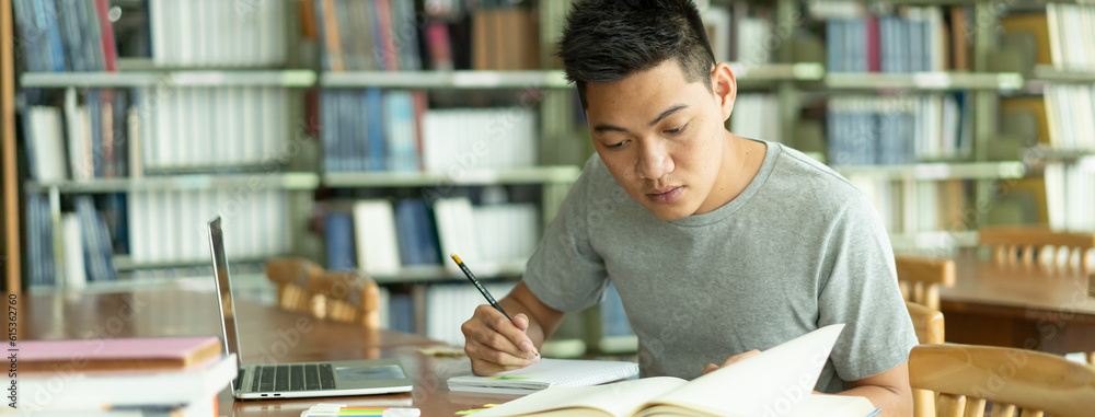 male asian student studying and reading book in library Stock Photo ...