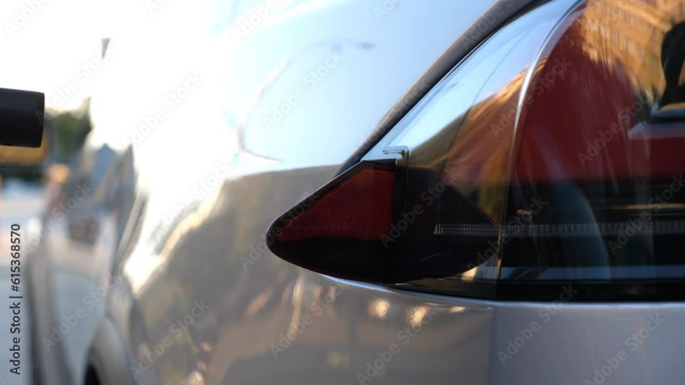 Hand opening an electric car charging socket cap and plugging in a ...