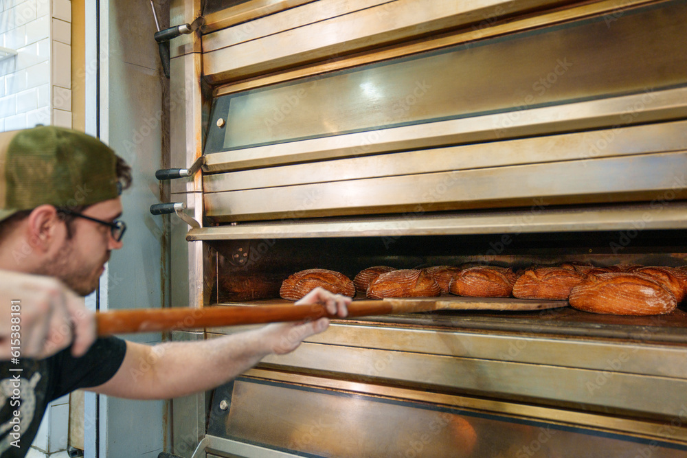 Capture the essence of craftsmanship as a young baker expertly loads ...