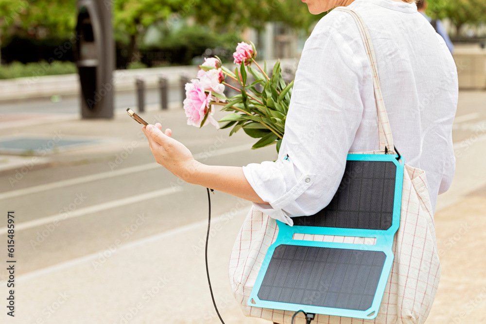 Solar battery charger for mobile devices. Woman in the city charging ...
