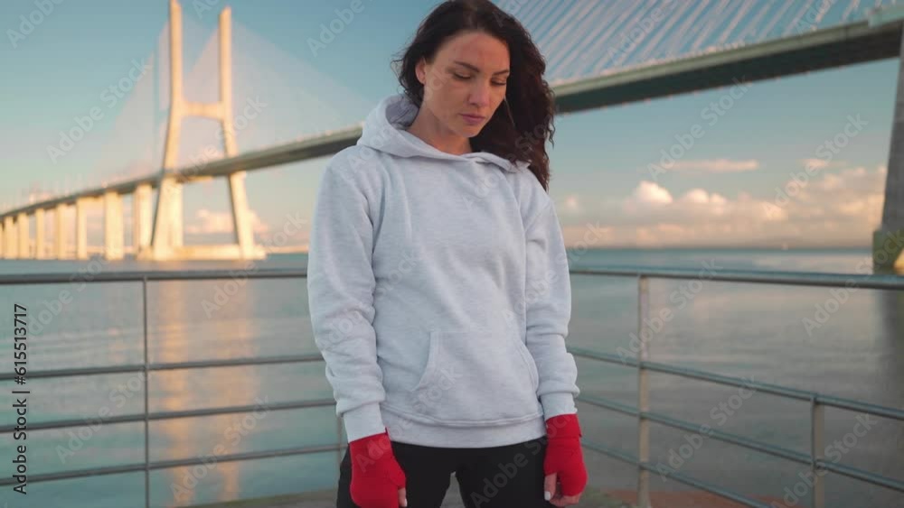 Boxer woman putting hood, looking camera and taking fighting pose ...