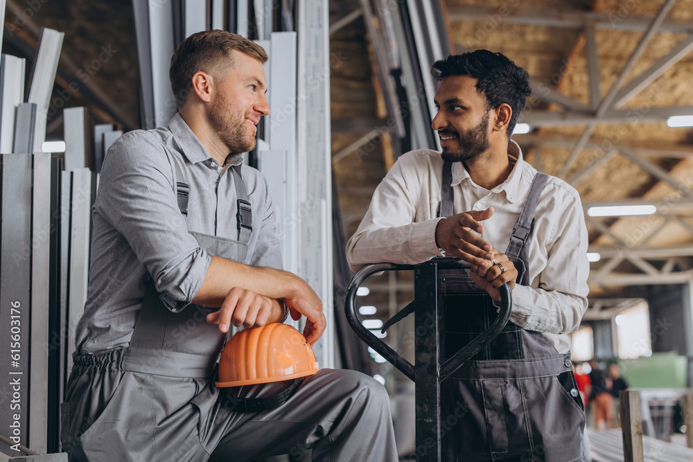 Portrait of two international workers wearing hardhats taking break ...