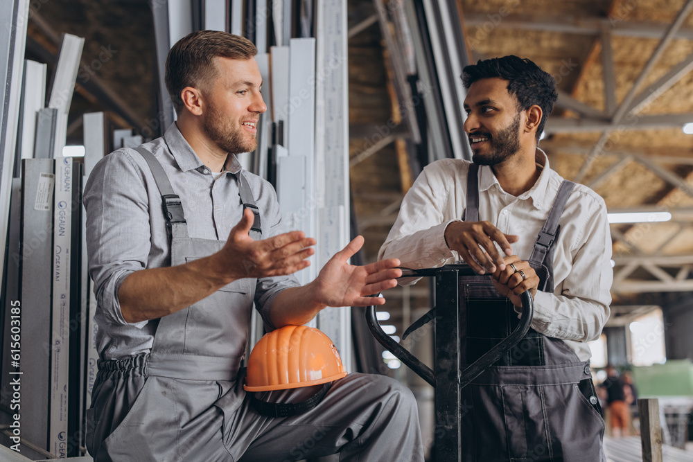 Portrait of two international workers wearing hardhats taking break ...