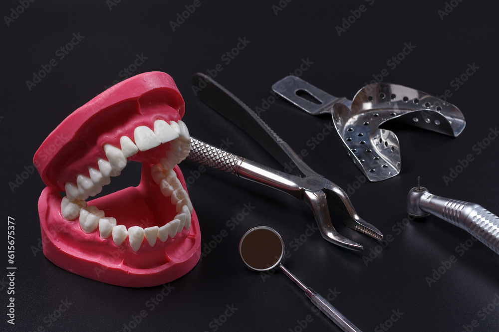 Stainless steel dental tools and layout of a human jaw on the black ...