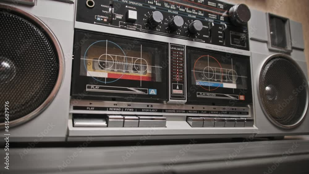 Playing audio cassette tape in vintage boombox player on the table ...