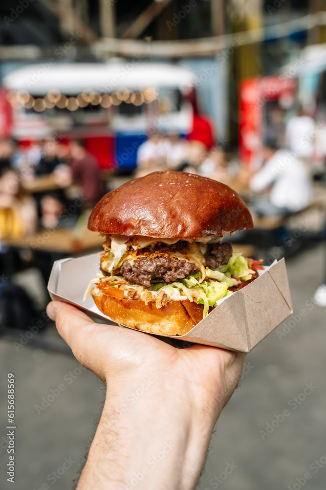 Street food burger on hand on hipster food market background. Grill and ...
