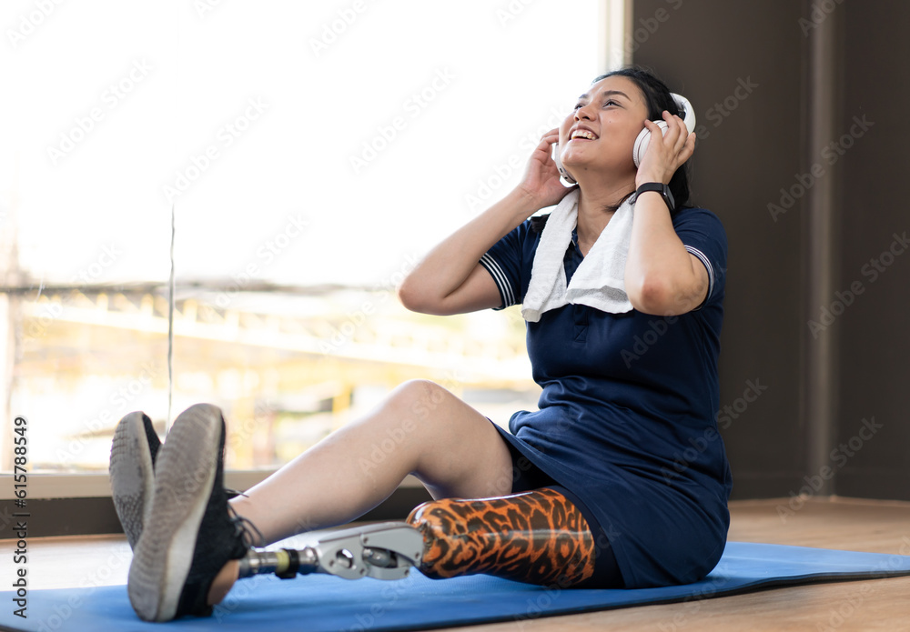 Prosthetic leg woman sitting on mat doing physical exercise in fitness ...