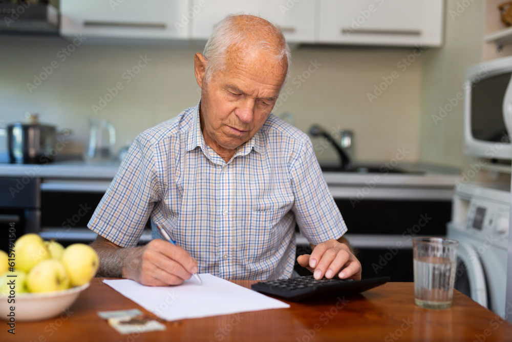 Elderly male sits at the table and looks through bills and checks Stock ...