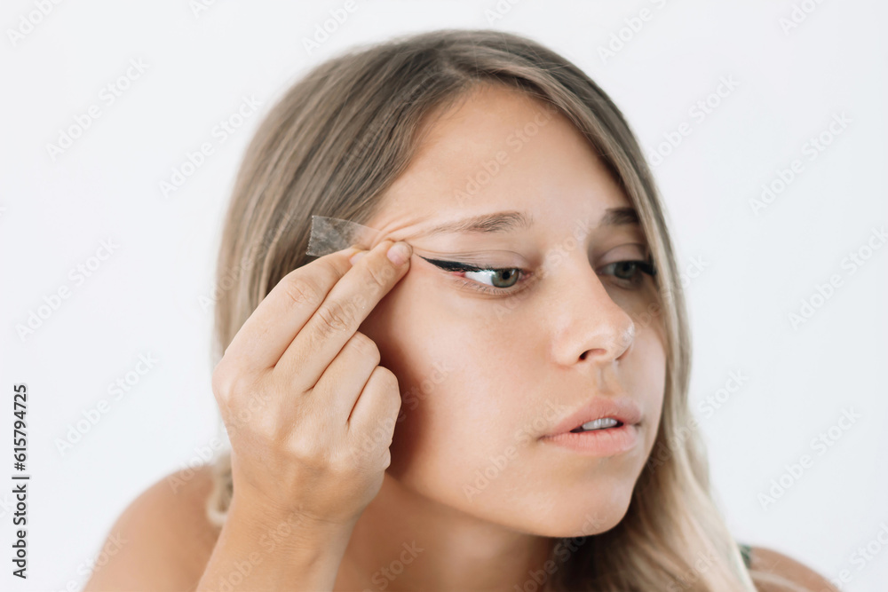 Young caucasian blonde woman wants to change her eye shape pulling ...