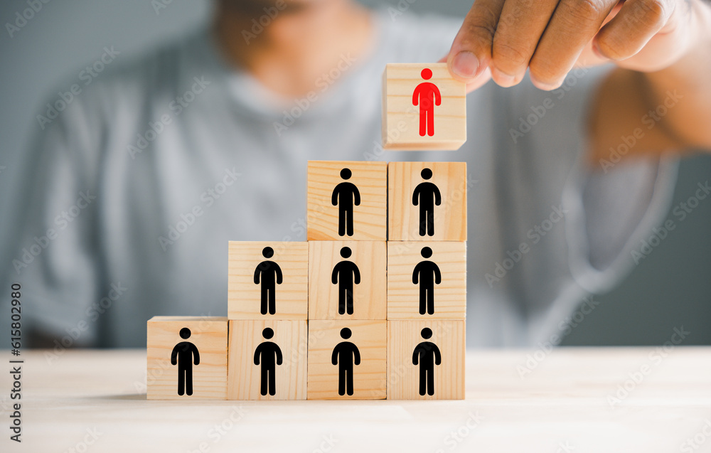 A hand carefully selecting man people icons on cube wooden toy blocks ...