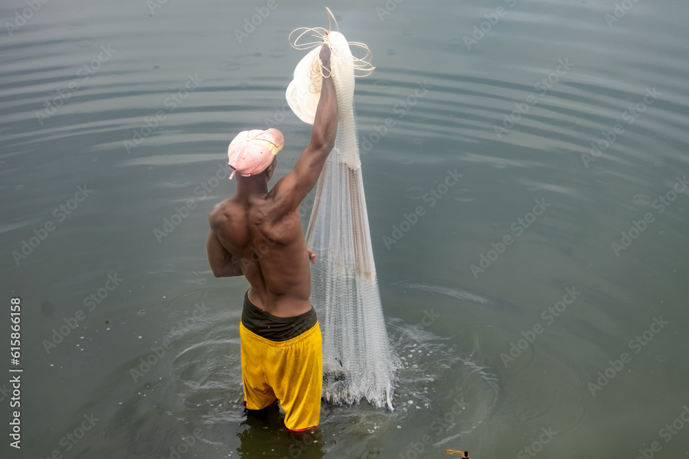 Foto de A young boy with a fishing net stands shirtless in a river ...