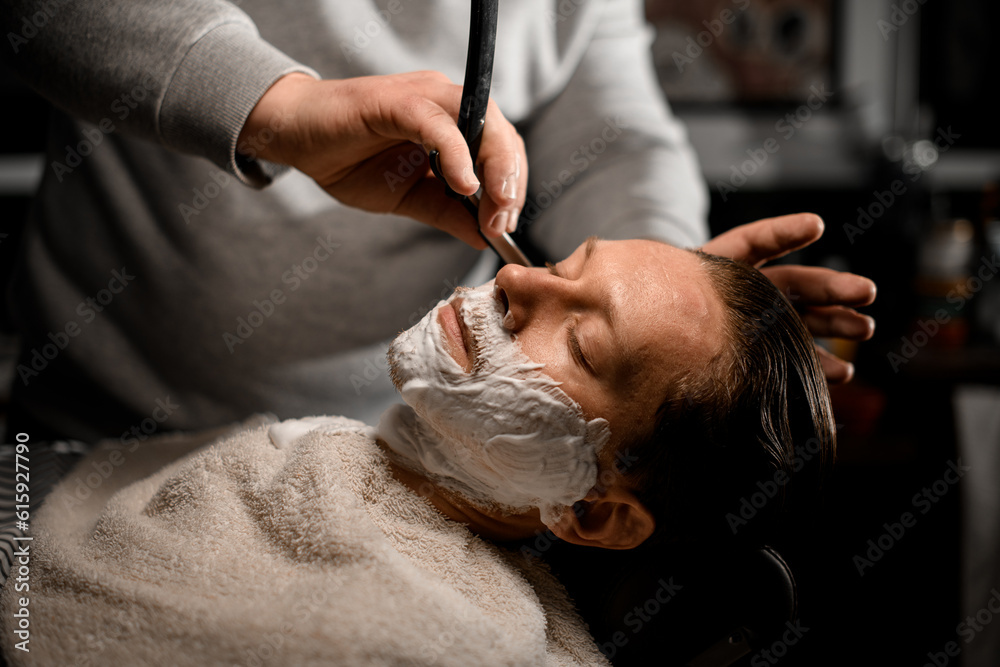 Barber man shaving young attractive client with vintage straight razor ...