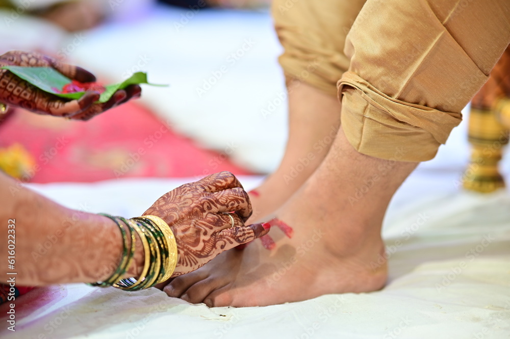 feet of a Indian Groom. Hands of mother drawing symbol on groom legs by ...