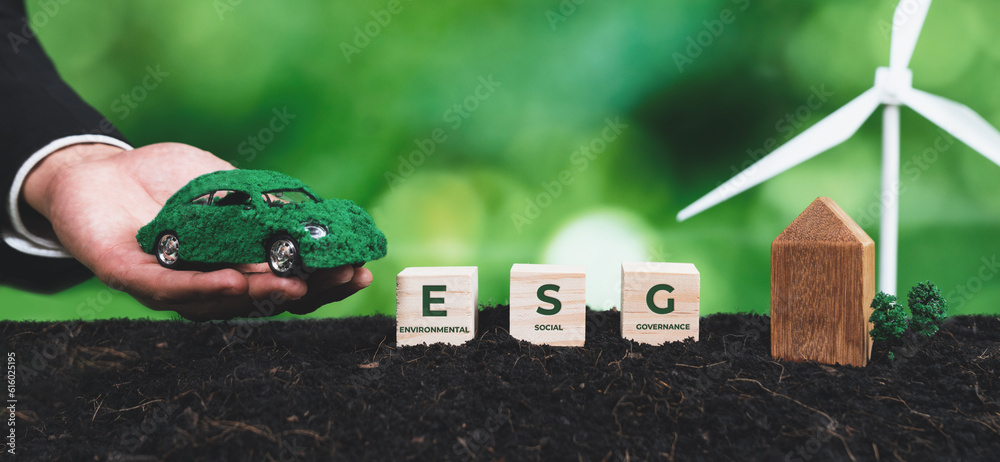 Businessman holding green car model with ESG symbol cube for corporate ...