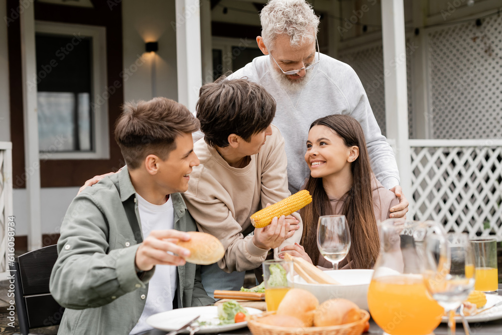 Smiling middle aged parents hugging teen daughter near son and tasty ...