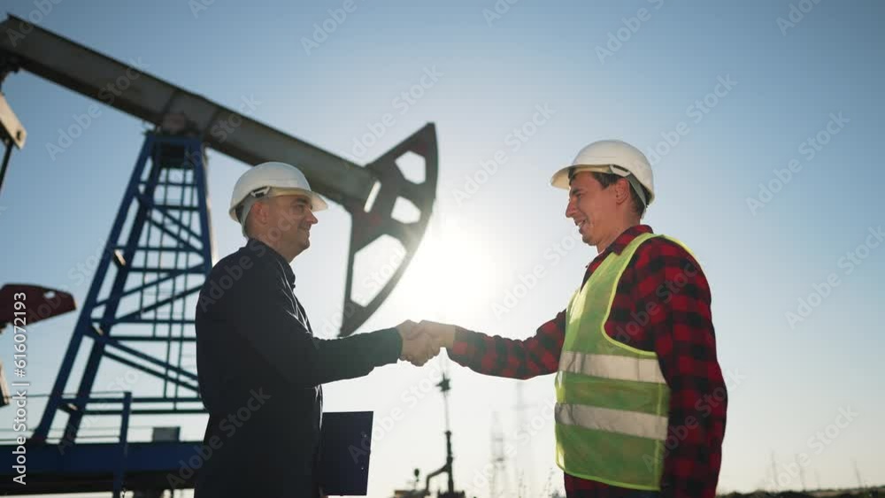Oil pump. Engineers handshake. Corporate contract. People in helmets ...