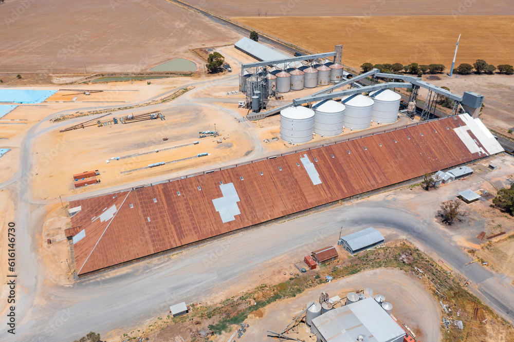 Aerial view of a long grain shed alongside silos and grain pits in a ...
