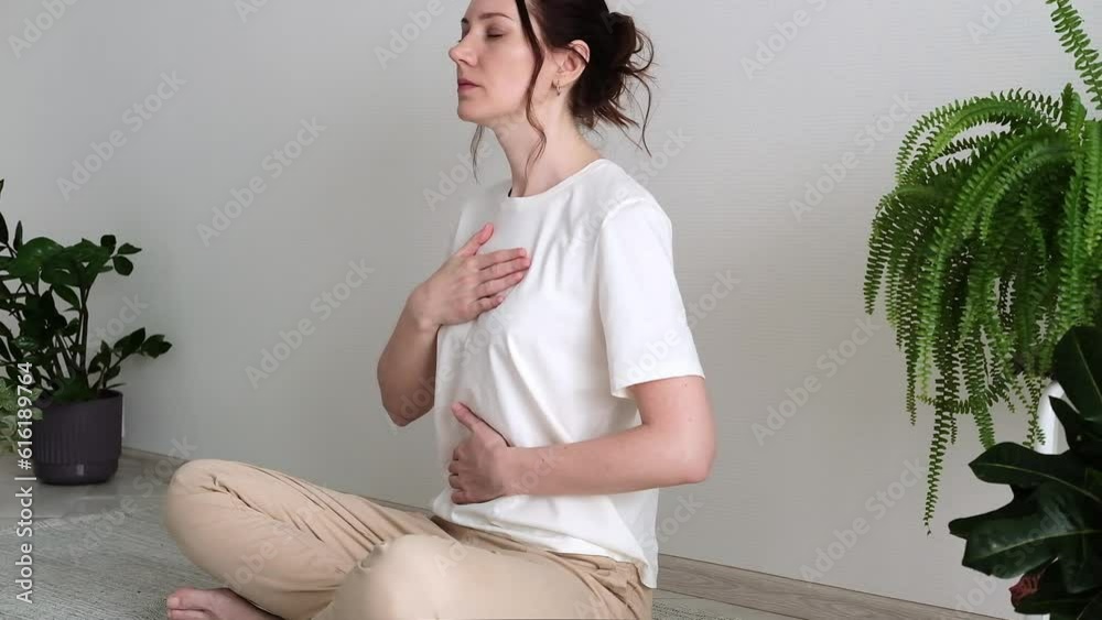 Pretty female sitting on the floor in lotus posture with hands on her ...