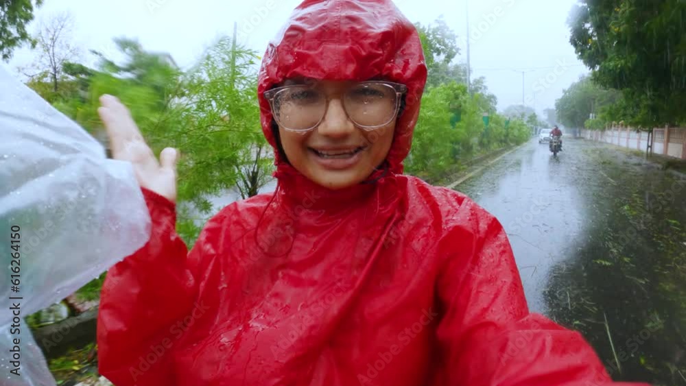 Portrait of Indian girl vlogger wearing raincoat and vlogging during ...