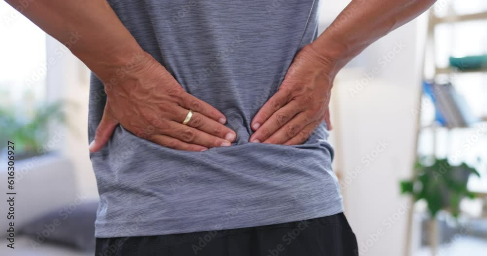 Hands, back pain and injury with a black man in his home, holding his ...