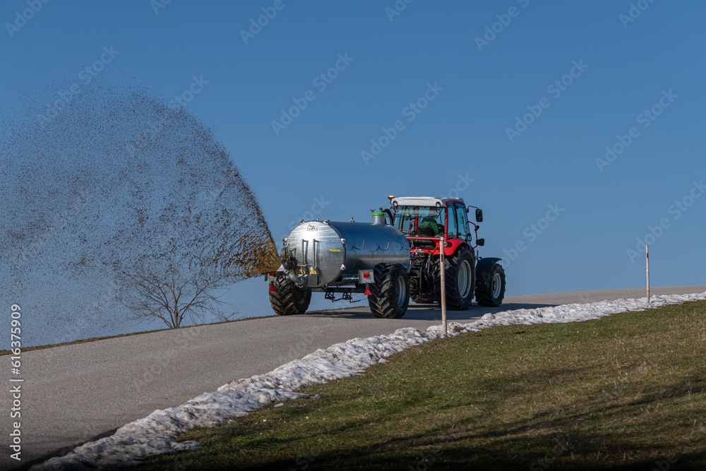 farmer on tractor with manure tank spreading liquid manure on farmland ...