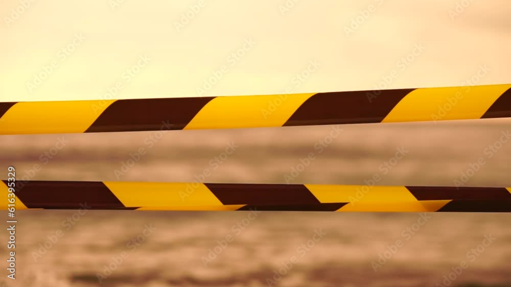 Yellow black warning tape barrier ribbon swinging in the wind across ...
