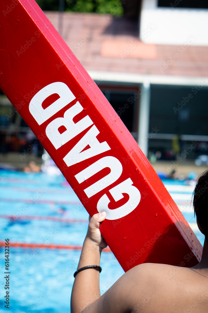 Red guard at swimming pool. Plastic tube lifesaving tool lying beside a ...