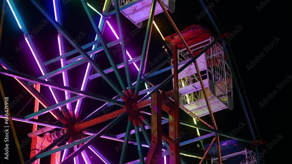 Radiating rainbow spirals of light on a ferris wheel in a foggy night ...