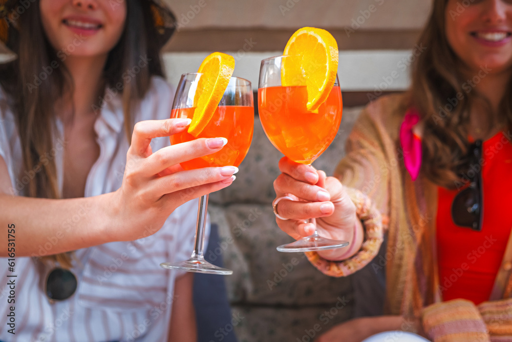 Close-up Toast with Spritz Cocktails - Two women toast with colorful ...