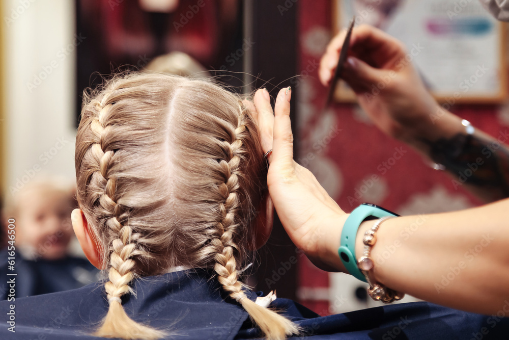Hair stylist braiding braids for pretty kid in barbershop, hair salon ...