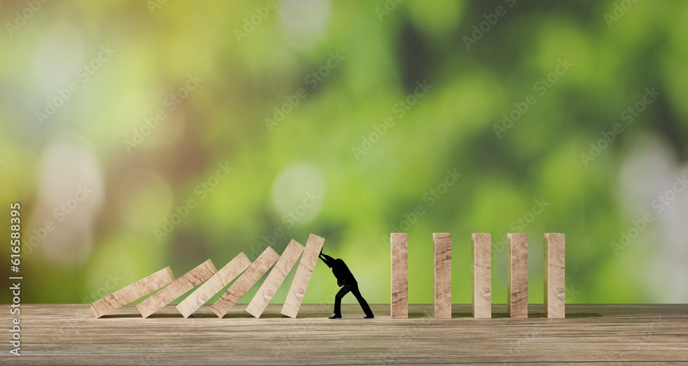Silhouette of a man in panic against collapsing wooden dominos ...