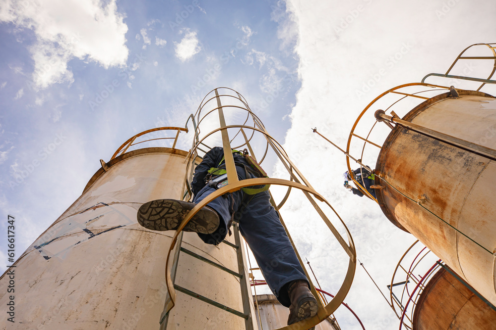 Refinery factory worker climbing up metal stairs ladder on industrial ...