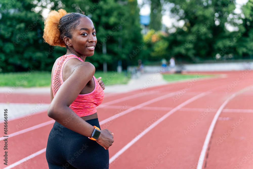 The confident black woman casually jogs on a running track, exuding ...