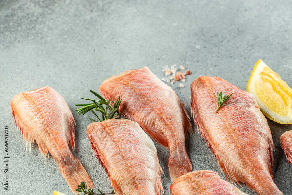 fish, red snapper with lemon, rosemary, salt on a light background ...