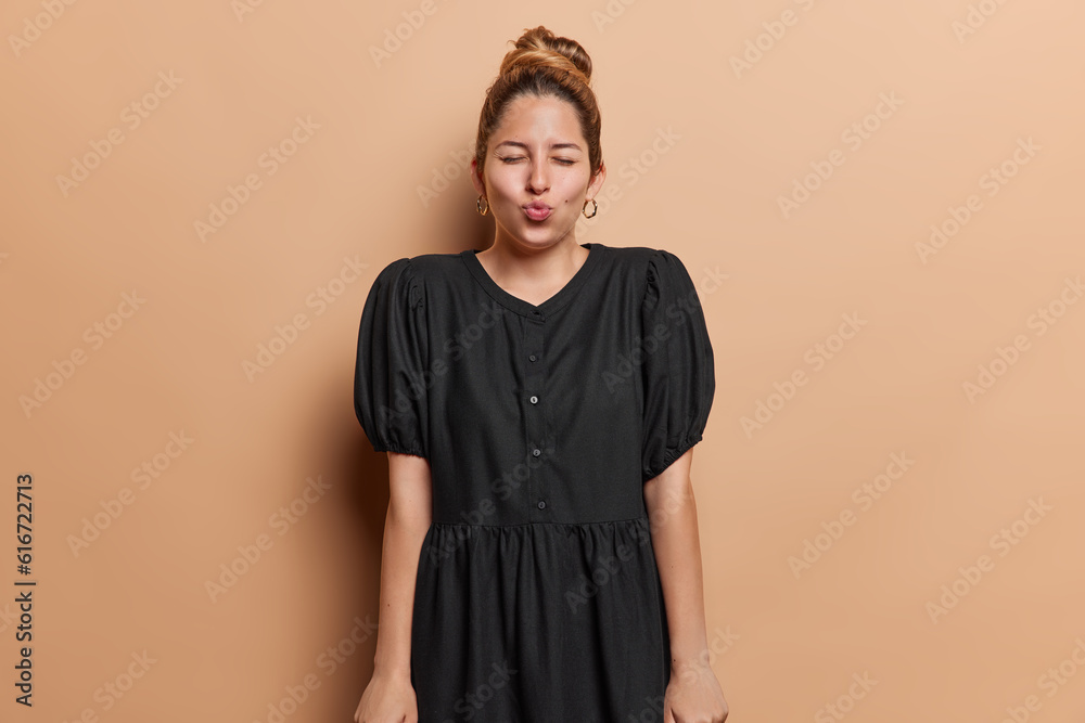 Pretty young woman with folded lips and expression of anticipation ...