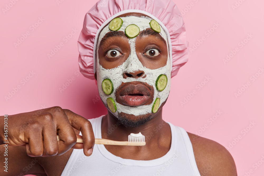 Shot of surprised dark skinned man holds toothbrush with toothpaste ...