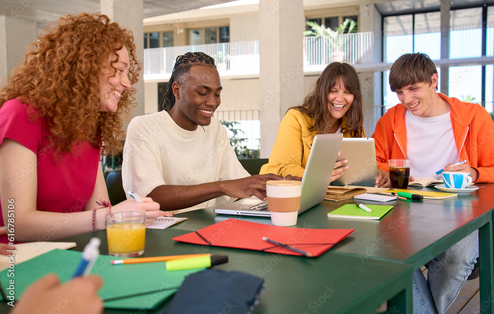 Smiling young people doing homework using laptop and tablet in college ...