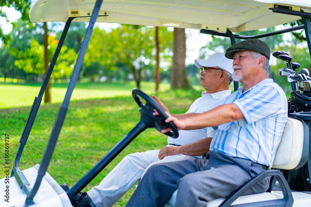 Asian senior man friends driving golf cart on the road at golf course ...