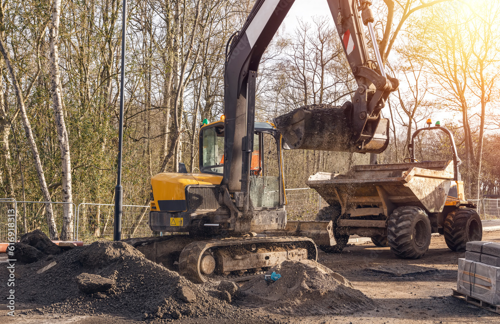 Excavator loading semi-dry concrete mix into dumper on construction ...