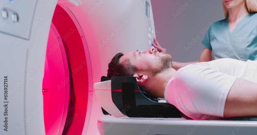 Shoot from side. Male patient is undergoing MRI tomography examination ...