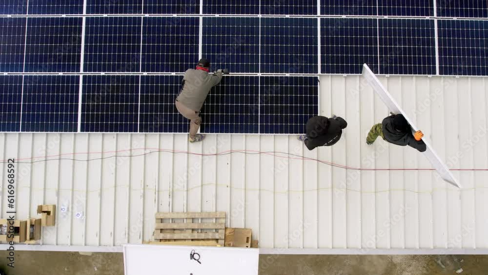 Modern solar panels produce clean electricity. Solar technician installing solar panels on house ...