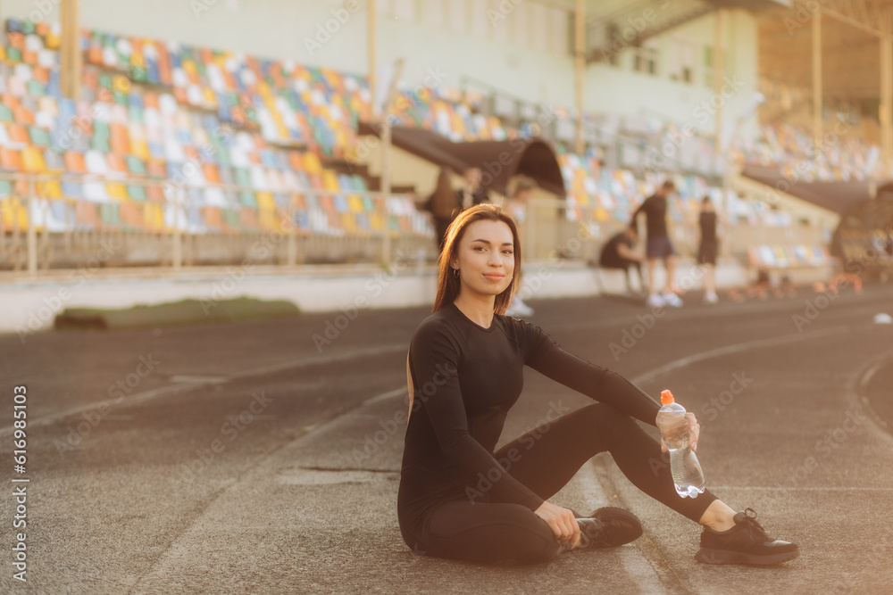 Sportswoman sitting and stretching on blue track field. Woman runner ...