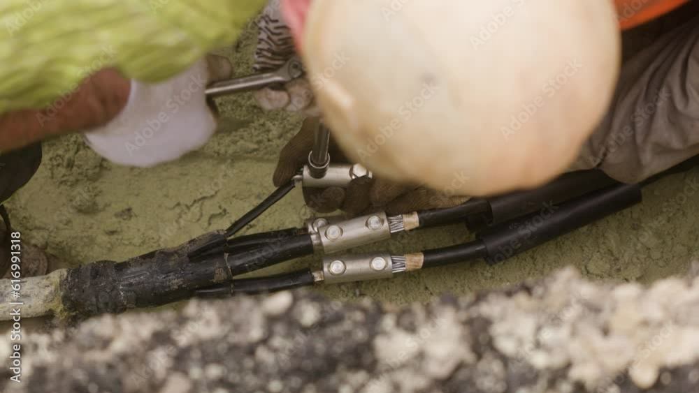 The worker is connecting two power transmission line cables and ...